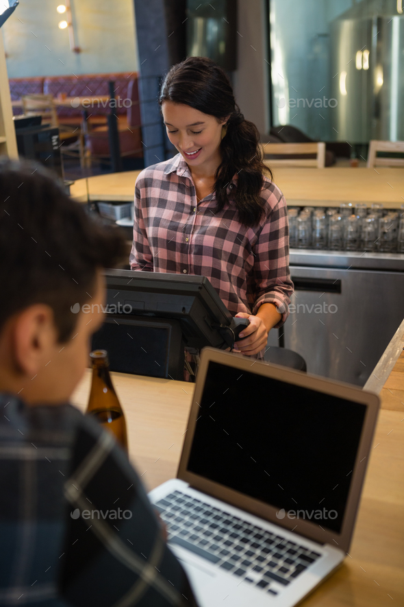 Female owner using cash register by customer at bar counter Stock Photo ...