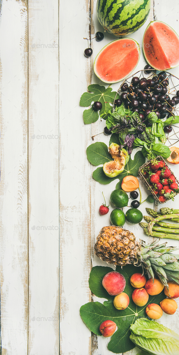 Seasonal fruit, vegetables and greens over wooden background, vertical ...