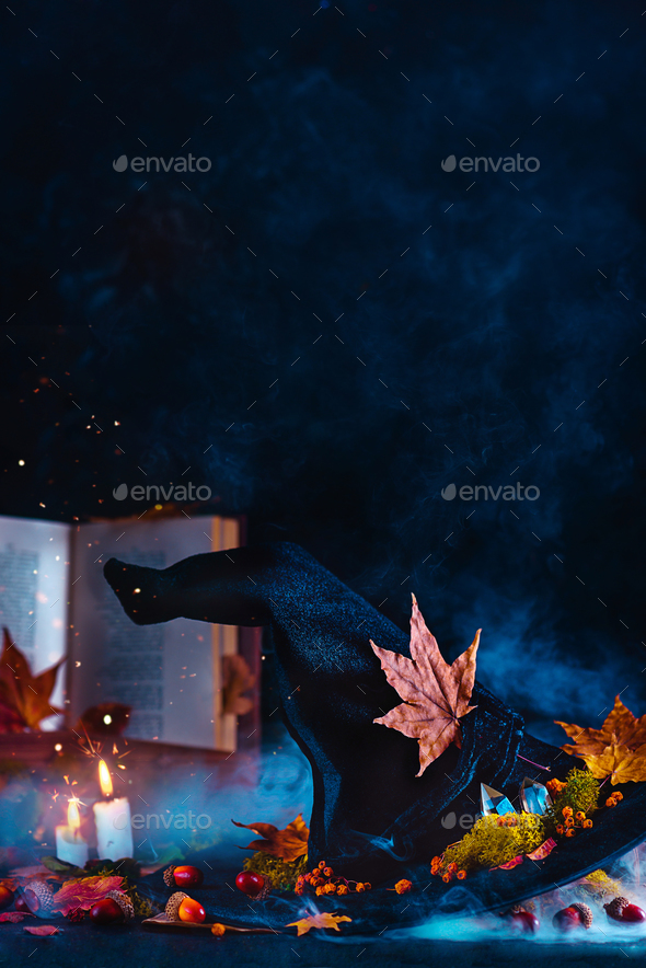 Witch hat in a spooky still life with candles, smoke and sparks. Occult ...