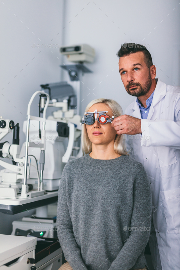 Optician checking patient's eyesight with trial frame. Stock Photo by ...