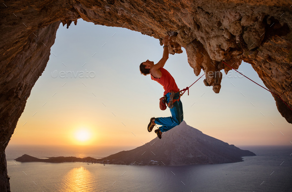 Male rock climber hanging with one hand on challenging route Stock ...