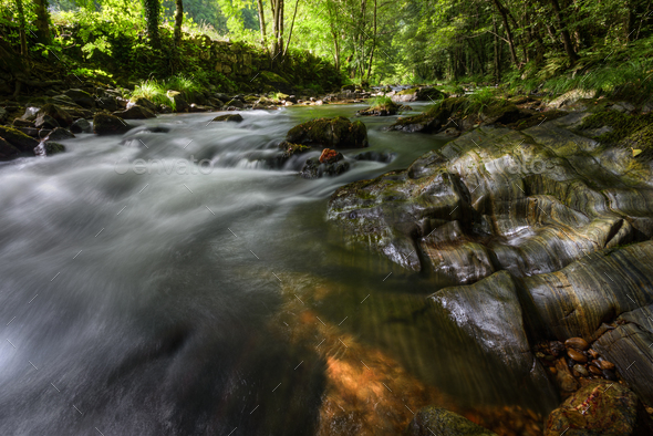 Striated limestone rock in the bed of a river Stock Photo by luisvilanova