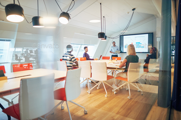 Manager and staff discussing graphs together during a boardroom meeting ...