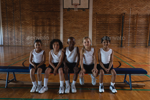 Front view of schoolkids looking at camera while sitting on bench at ...