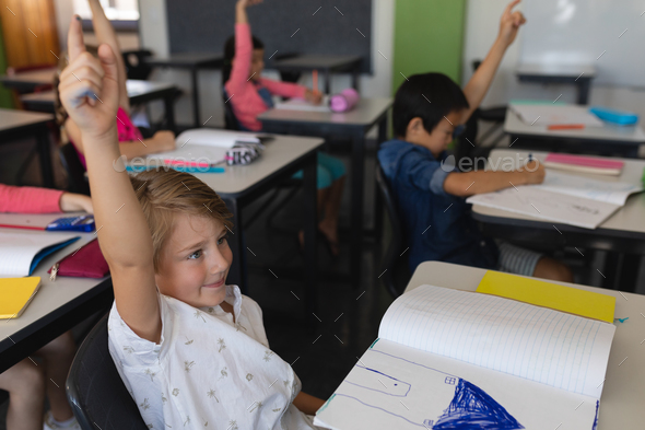 Side view of school kids raising hand in classroom Stock Photo by ...