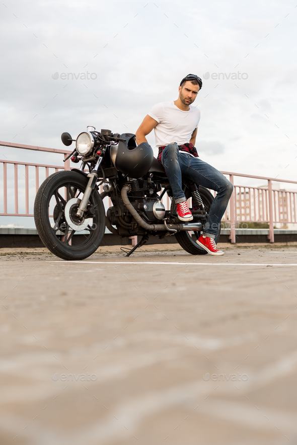 Brutal man sit on cafe racer custom motorbike. Stock Photo by nikkolia