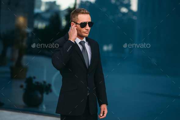 Male bodyguard uses security earpiece outdoors Stock Photo by NomadSoul1