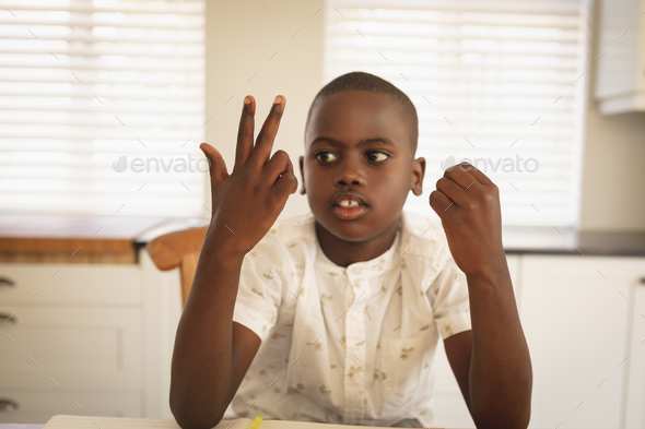Front view of thoughtful African American boy doing homework on dining ...