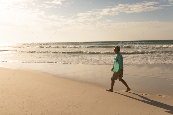 Man Walking On Beach At Sunset