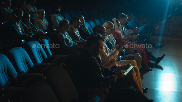 Side view of mixed race audience sitting in the auditorium and holding ...