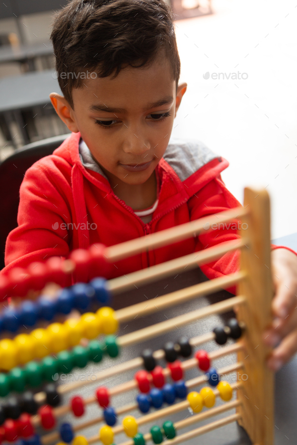 Schoolboy learning math with abacus at desk in a classroom at ...