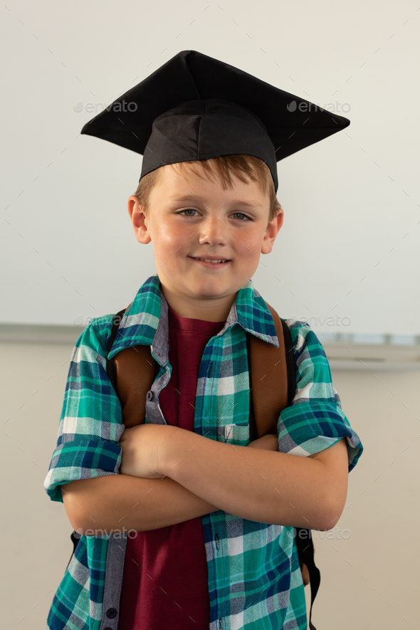 Front view of happy Caucasian boy in graduation cap standing in a ...