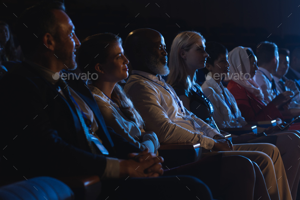 Side view of mixed race business colleagues sitting and watching ...