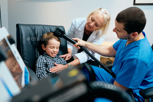 Paediatrician Doctor Doing Brain Treatment To Autistic Child In Clinic ...