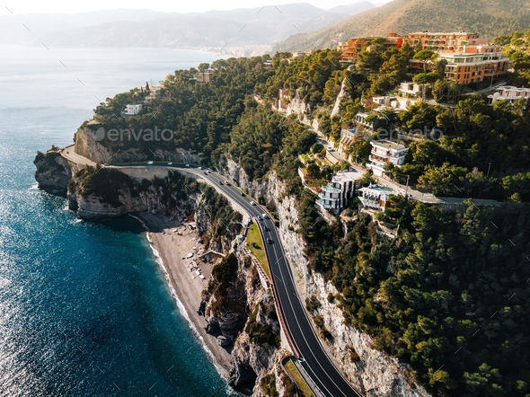 Aerial view of road going through beautiful landscape by the sea in ...