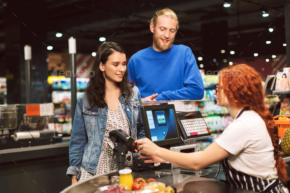 Beautiful smiling couple standing near cashier desk while happil Stock ...