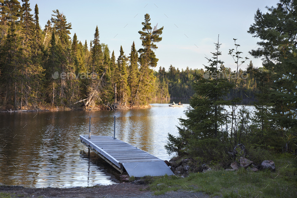 Northern Minnesota lake at sunset with dock and fishermen in the ...