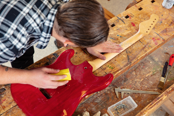 Top view of craftsman sanding a guitar neck in wood at workshop Stock ...