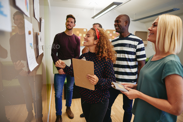 Smiling coworkers going over paperwork together on an office wall Stock ...
