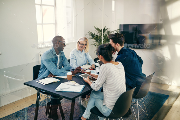 Smiling group of businesspeople talking together in an office boardroom ...