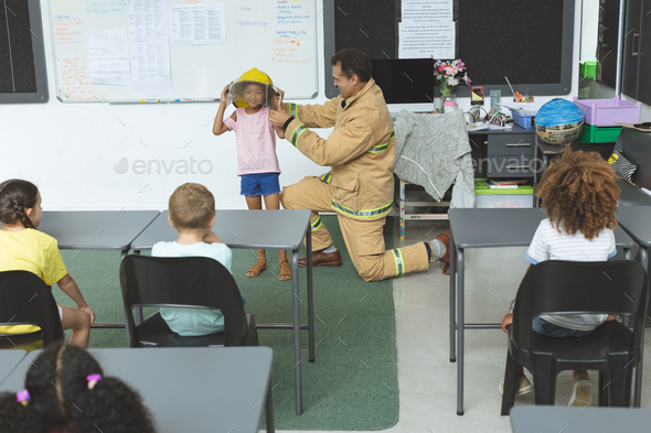 firefighter teaching to schoolgirl about fire safety in classroom Stock ...