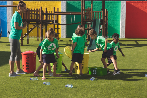 Students putting plastic bottles on dustbin in schoolyard Stock Photo ...