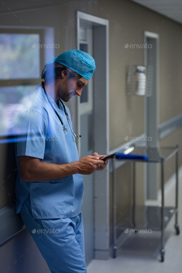 Male surgeon using mobile phone in the hospital corridor Stock Photo by ...