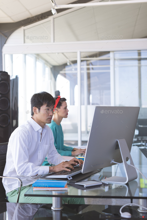 Side view of Multi-ethnic business people working on computer at desk ...