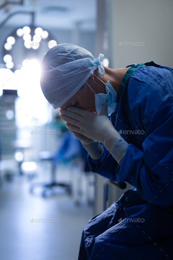 Upset female surgeon sitting on the operation bed in operation room ...
