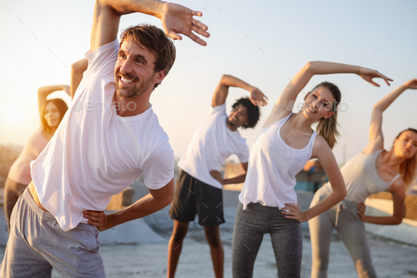 Group of athletic young people, friends in sportswear doing exercises ...