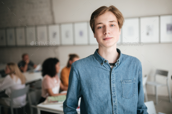 Cool boy in denim shirt standing in classroom with students on ...