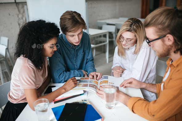 Group of young people sitting at the table and working together Stock ...