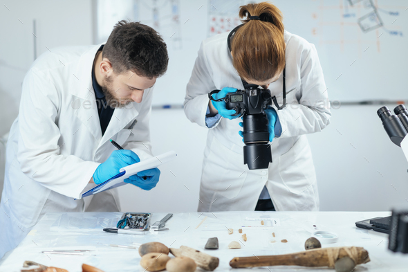 Archaeology Researchers in Laboratory, Documenting Artifacts with Camera Stock Photo by microgen