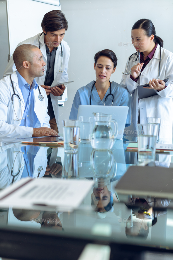 Diverse medical team discussing over laptop at the table of conference ...