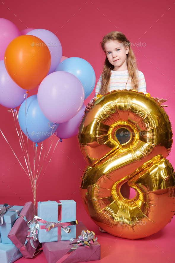 Cute little girl holding golden balloon in form of number eight Stock ...