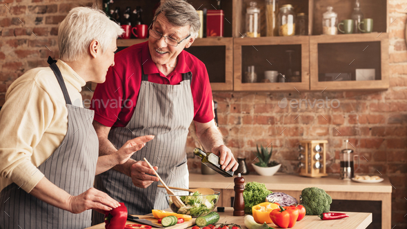 Laughing seniors cooking vegetable salad at kitchen Stock Photo by ...