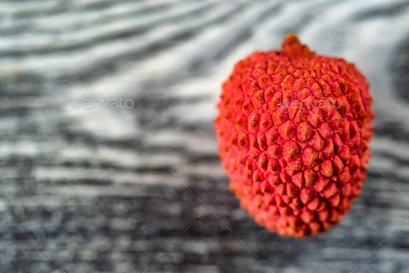 Single lychee on wooden background close Stock Photo by Yakov_Oskanov