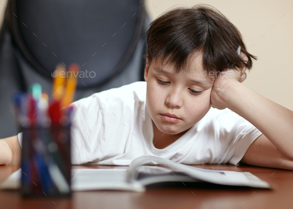 School boy studies hard over his book at home Stock Photo by Grey_Coast ...