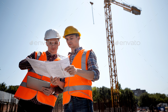Architect and construction manager dressed in orange work vests and ...