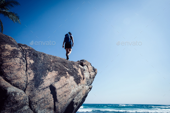 Brave woman backpacker walking on the cliff edge at seaside Stock Photo ...