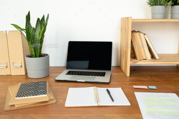 Wooden shelf with books, open copybook with pen, laptop and stack of ...