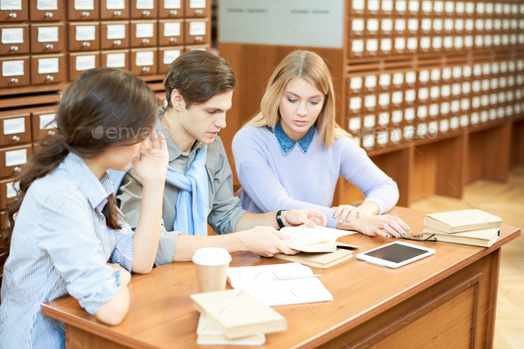 Busy students studying in library Stock Photo by seventyfourimages