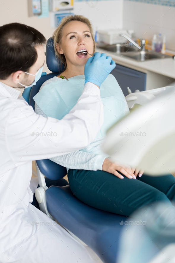 Man exploring teeth of woman in seat Stock Photo by seventyfourimages