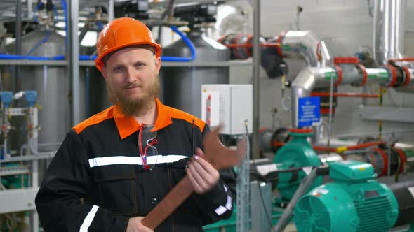 A Bearded Operator in an Orange Helmet Holds a Large Wrench in His ...