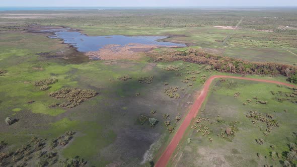 High Slow moving Drone shot of Red Road and Green Bushland and Water ...