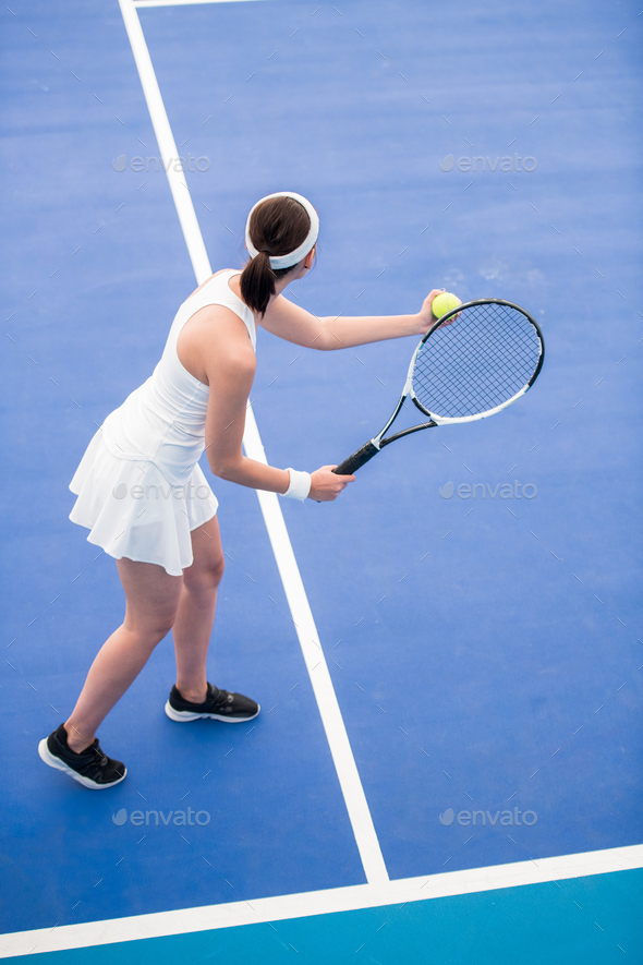 Tennis Player Serving Ball in Court Stock Photo by seventyfourimages