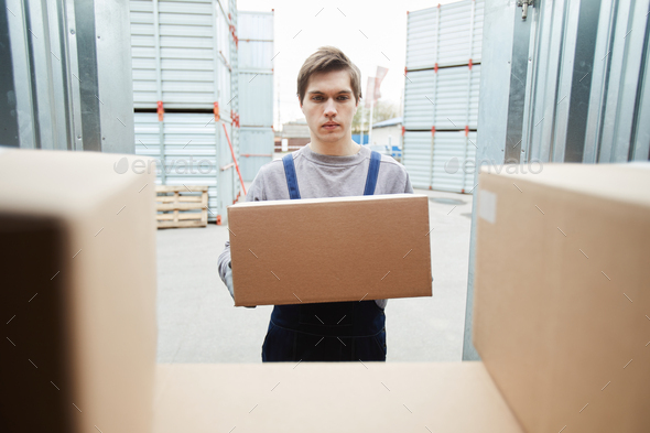 Young worker putting box in container Stock Photo by Pressmaster ...
