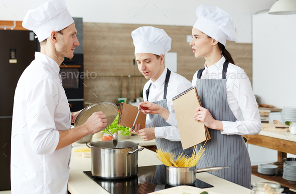 Cooking students questions at practical class Stock Photo by Pressmaster