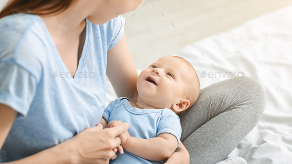 Adorable little baby smiling while lying on mother's laps Stock Photo ...