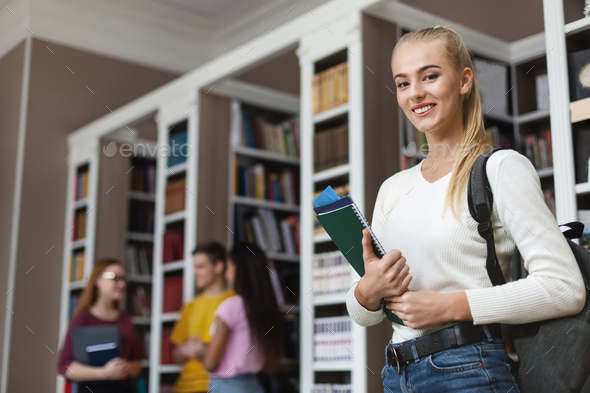 Pretty young girl smiling on library background Stock Photo by Prostock ...